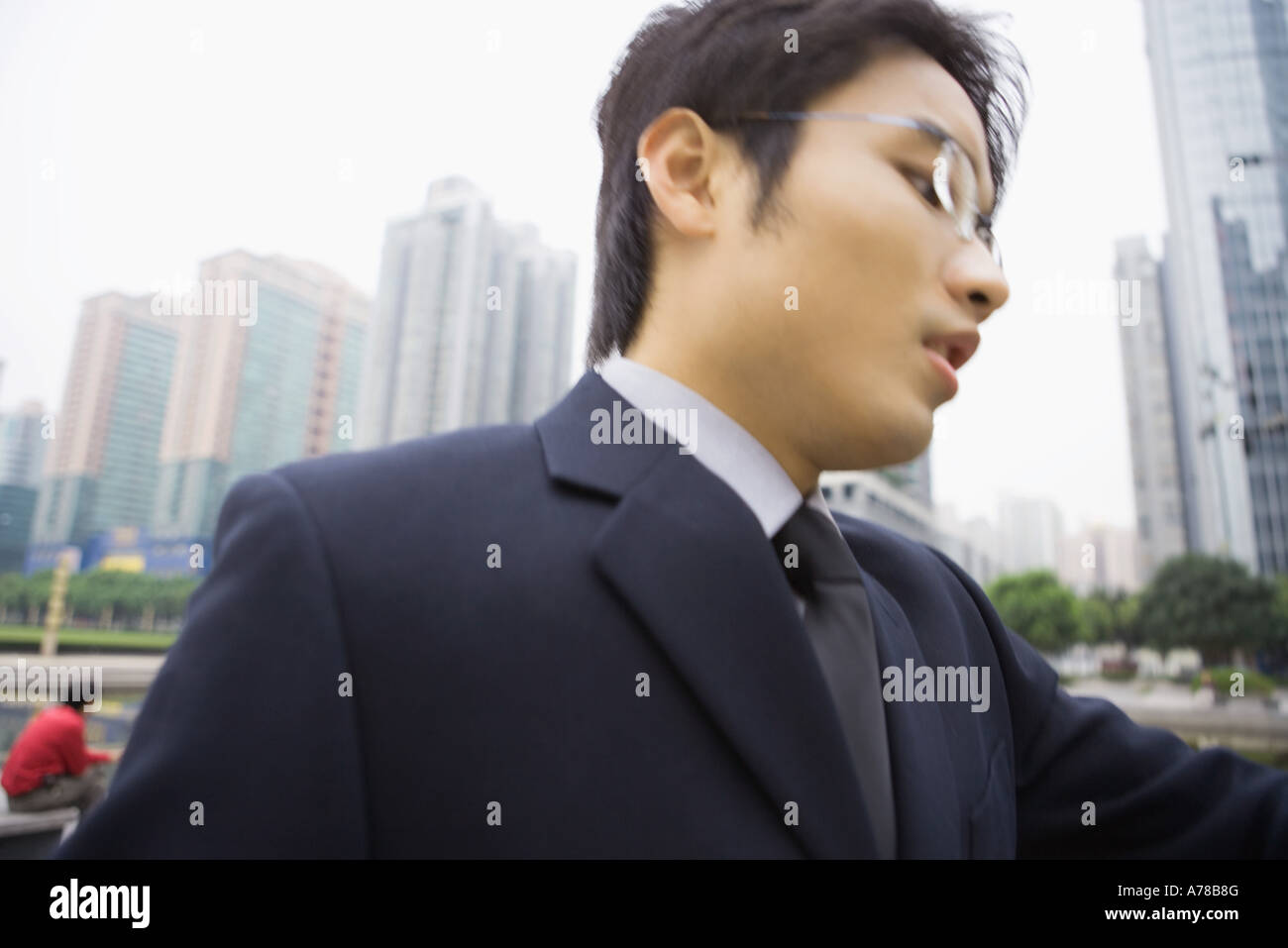 Businessman looking down, high rises in background Stock Photo - Alamy