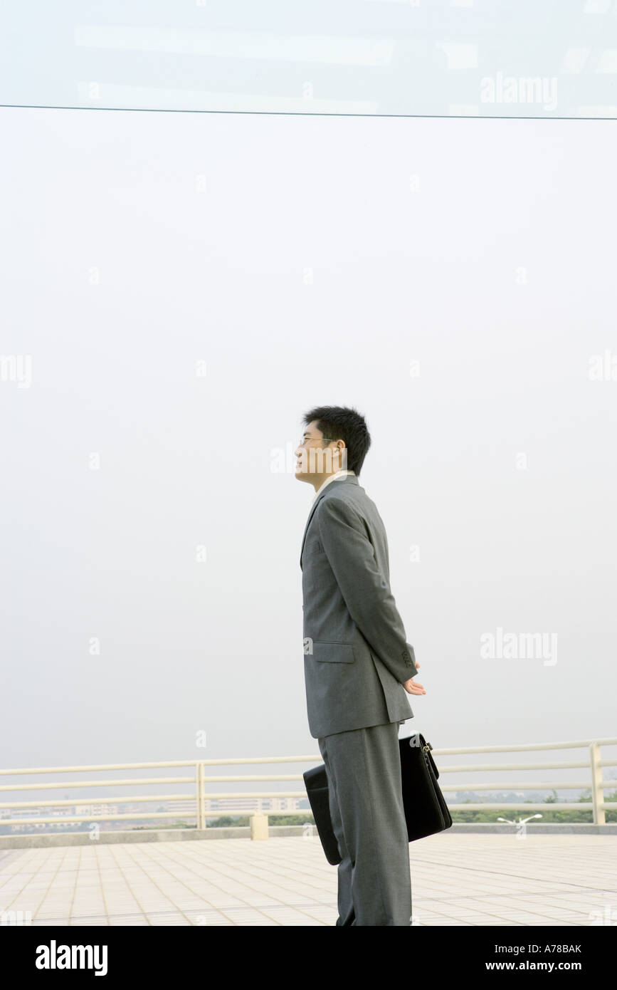Businessman standing on terrace, looking toward distance Stock Photo ...