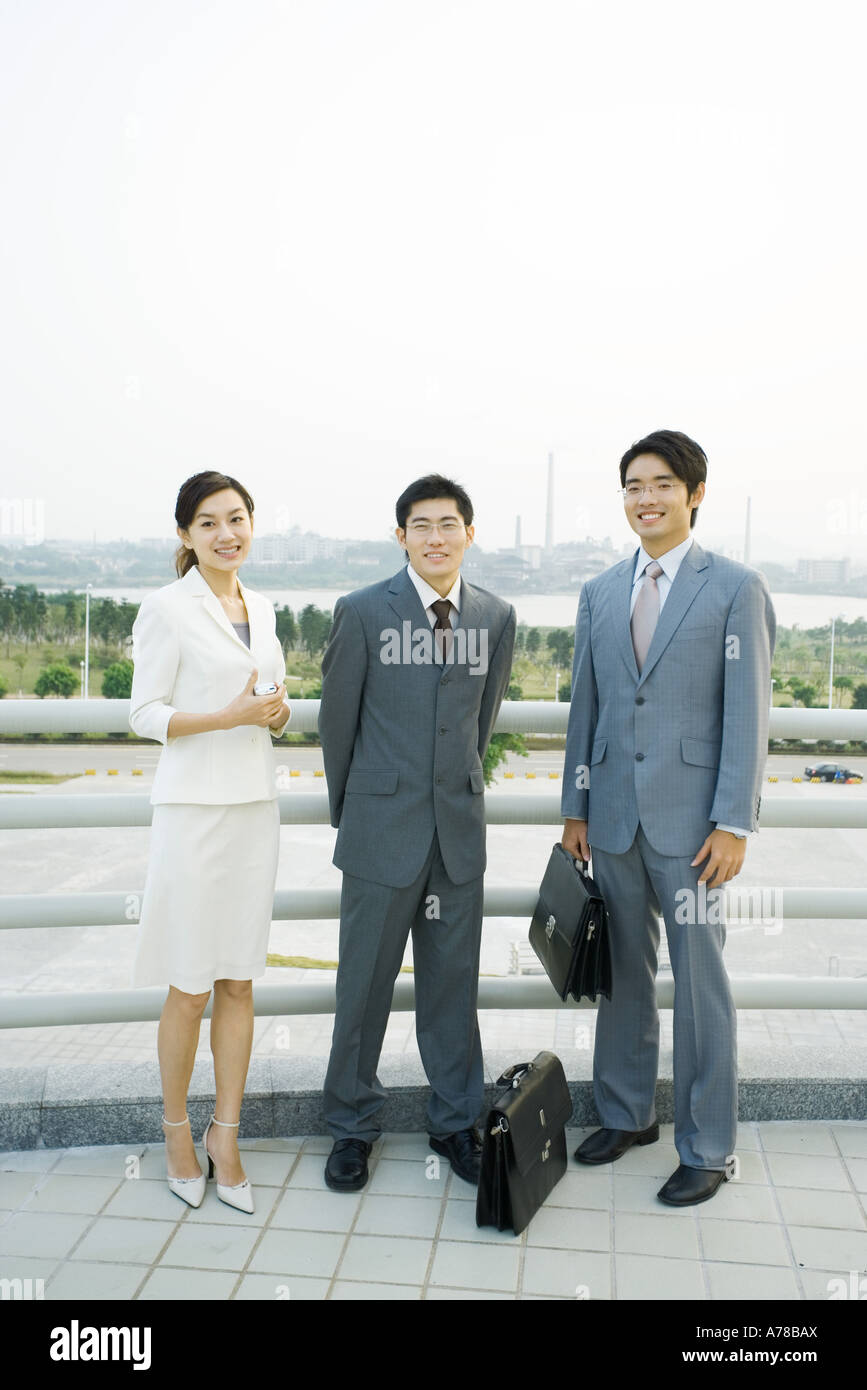 Three business executives standing by railing, looking at camera, full ...