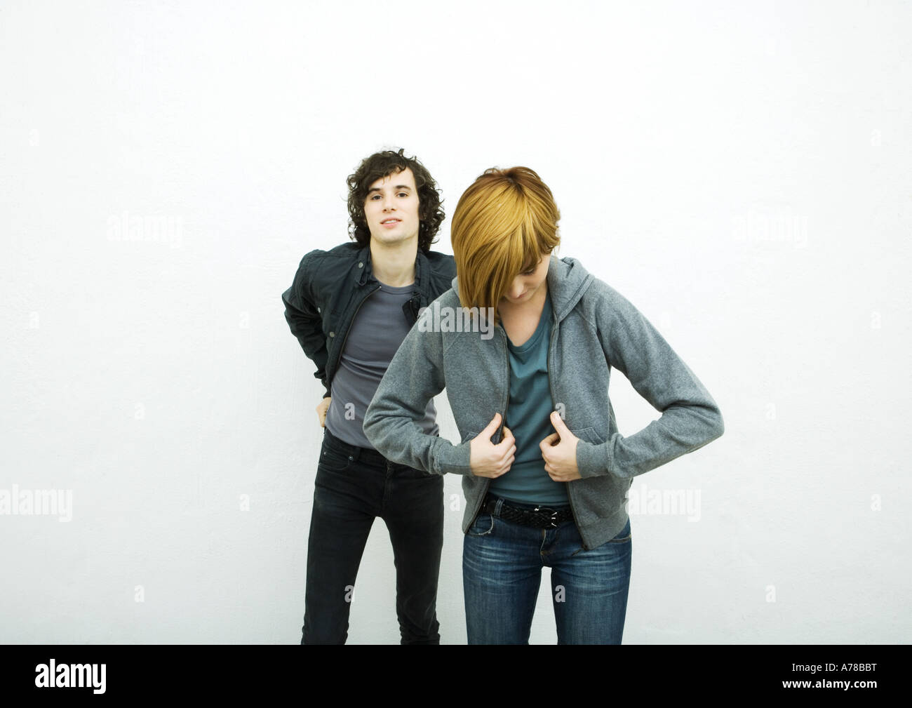 Two young adults putting on jackets, white background Stock Photo - Alamy