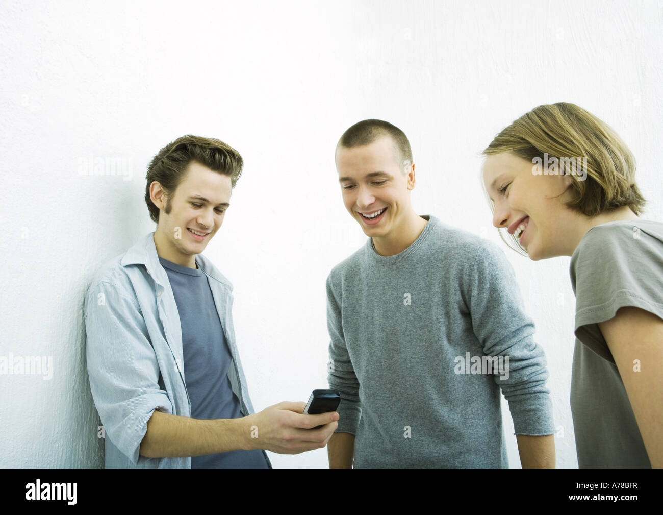 Three young friends looking at cell phone, smiling Stock Photo - Alamy