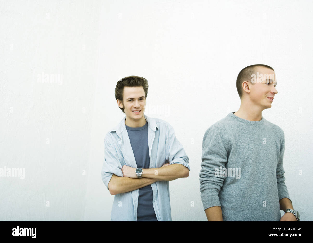 Two young adult men, one looking at camera, the other looking away ...