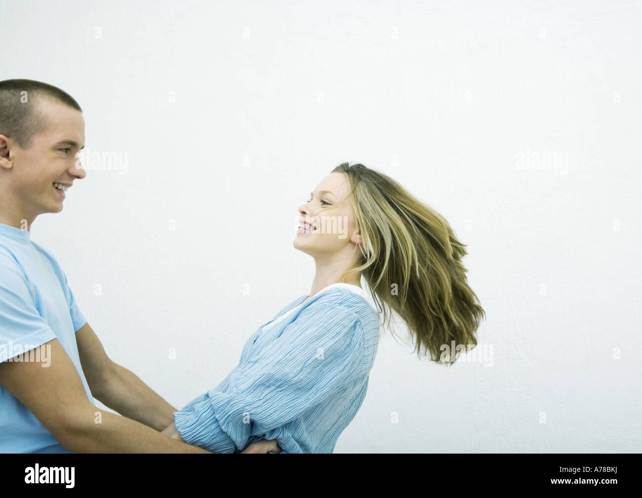 Young couple spinning around, white background Stock Photo - Alamy