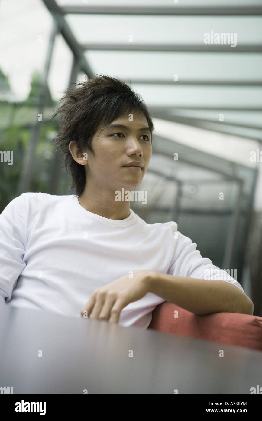 Young man sitting, looking out of frame Stock Photo - Alamy