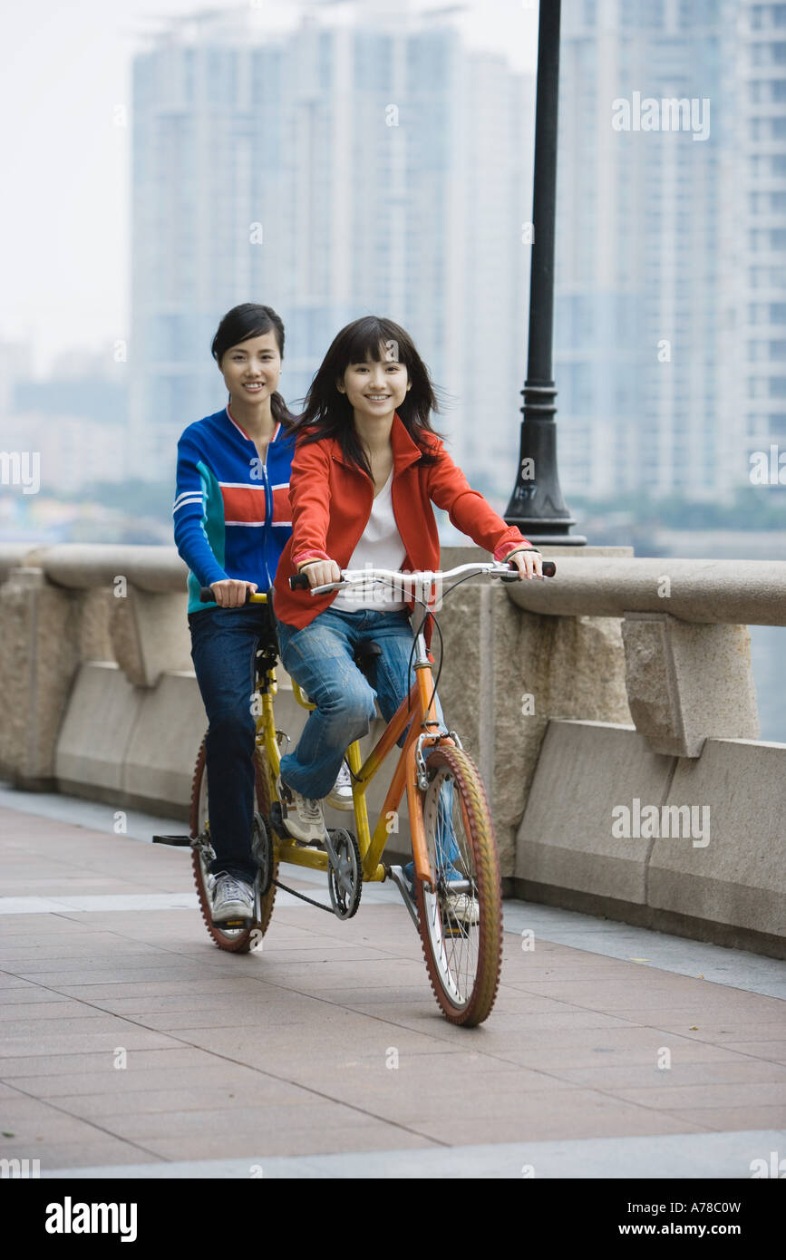 Two young women riding tandem bicycle Stock Photo - Alamy