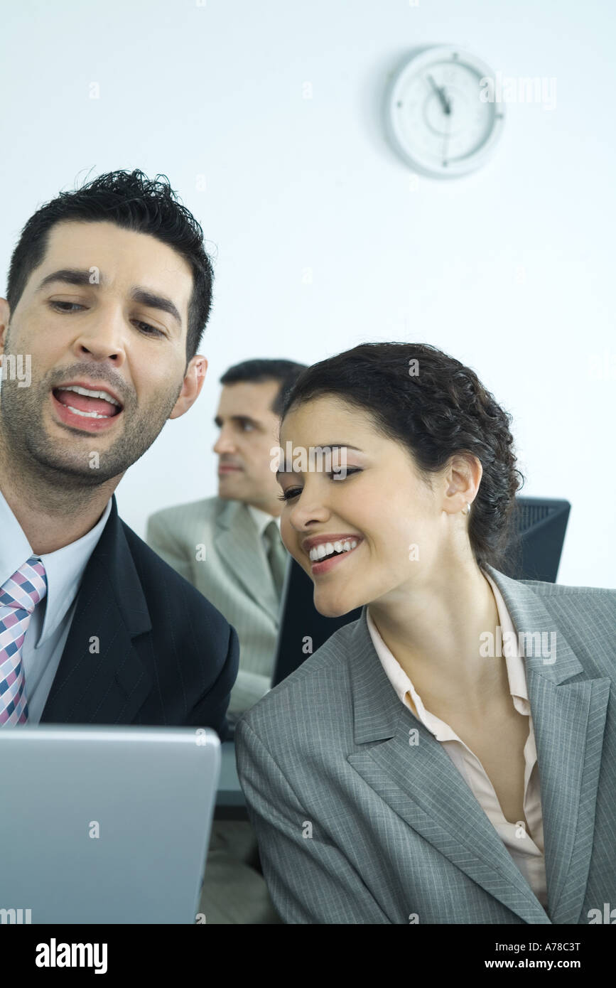 Three businessmen talking over laptop in office lobby Stock Photo - Alamy