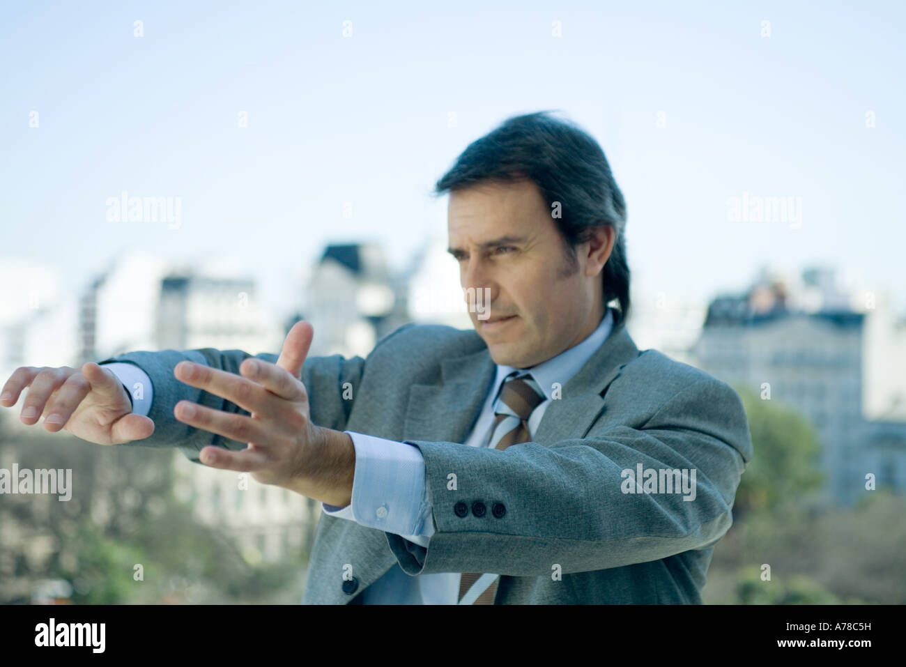 Businessman holding arms out in front of him and pointing, looking out ...