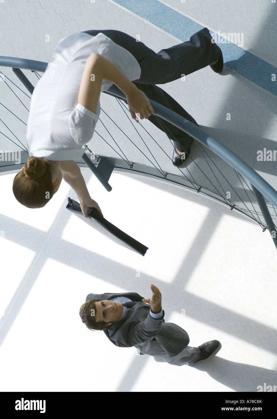 Woman leaning over railing, handing man briefcase Stock Photo - Alamy