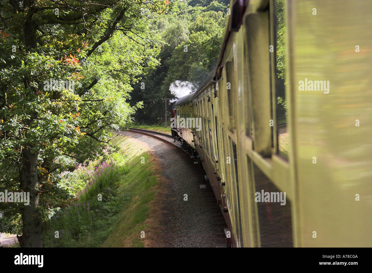 steam train travelling through countryside in the Lake District in ...