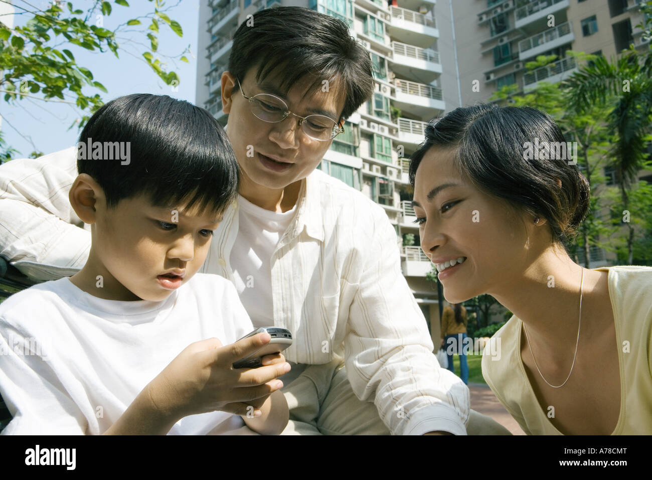 Family, boy using cell phone while parents watch Stock Photo - Alamy