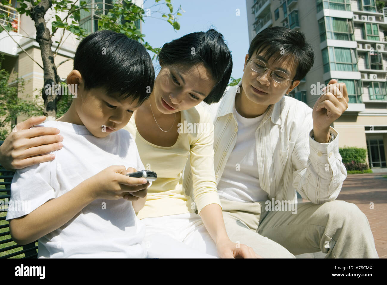 Family, boy using cell phone while parents watch Stock Photo - Alamy
