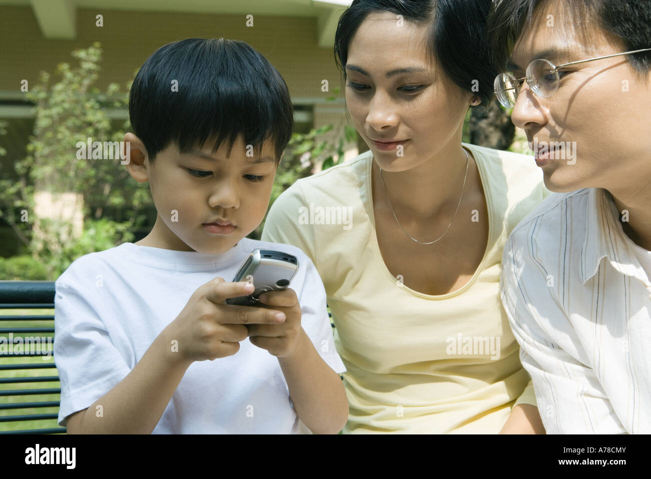 Family, boy using cell phone while parents watch Stock Photo - Alamy
