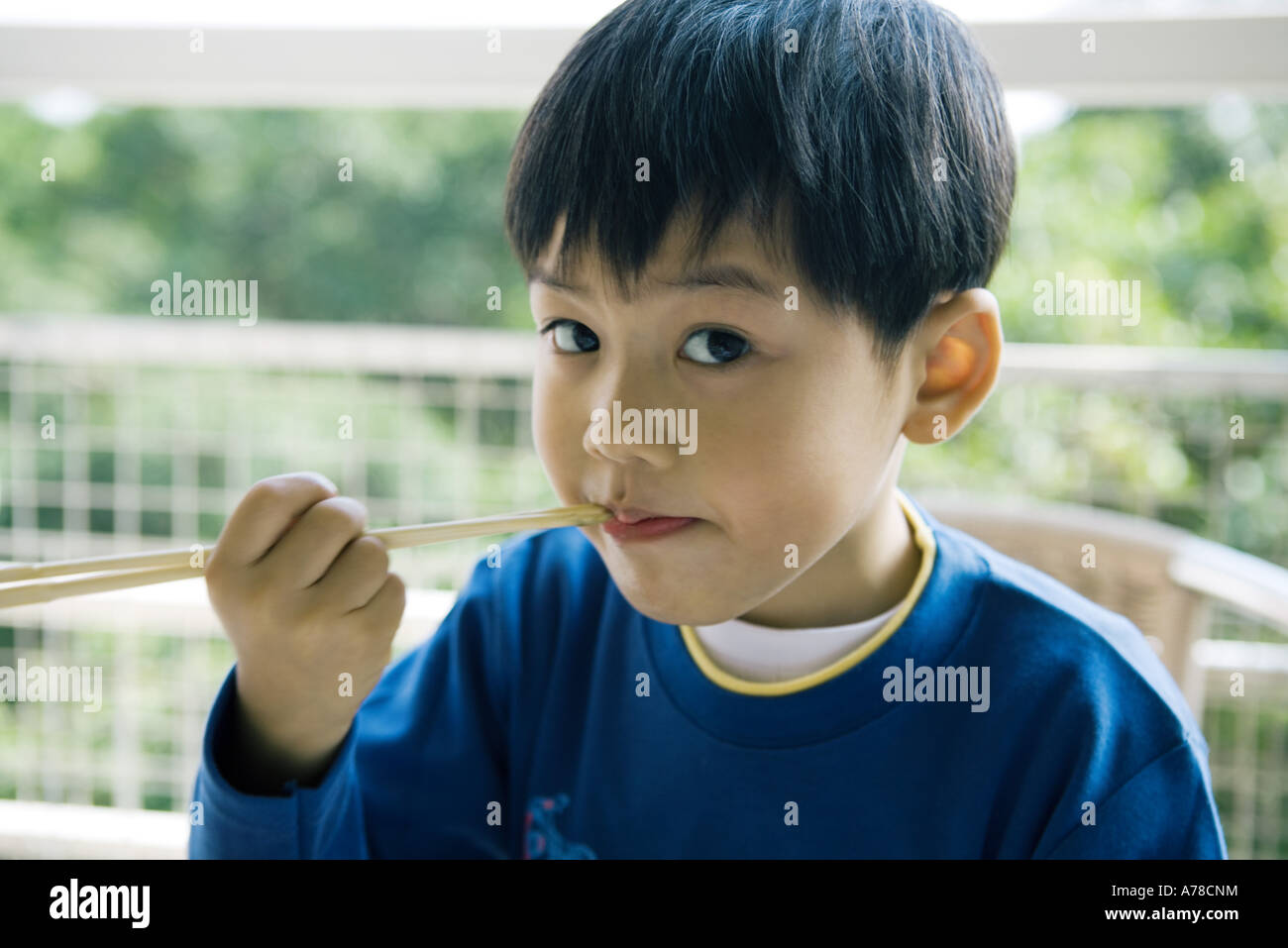 Boy eating with chopsticks Stock Photo - Alamy