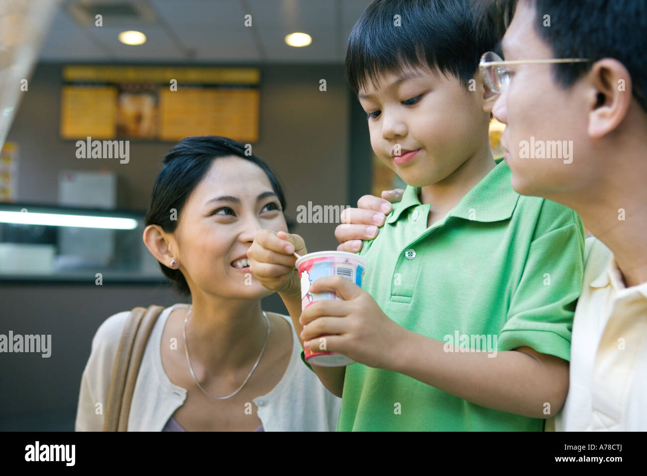Boy eating sweet snack, parents watching Stock Photo - Alamy
