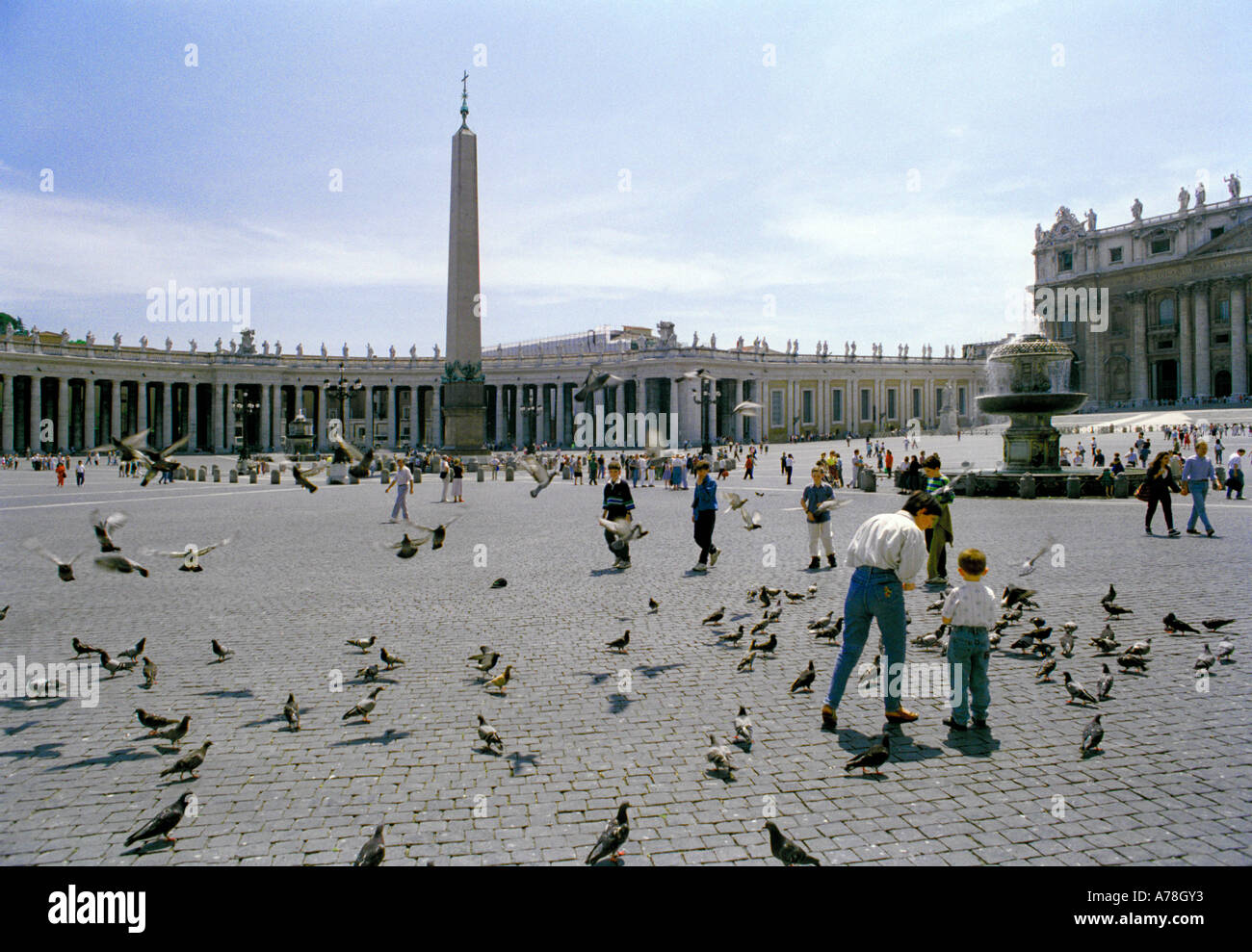 Feeding the pigeons in front of the imposing columns of St.Peter's ...