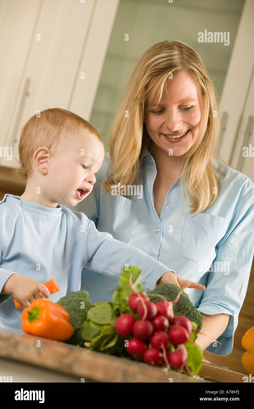 young mother and child cooking together in kitchen playing with organic ...