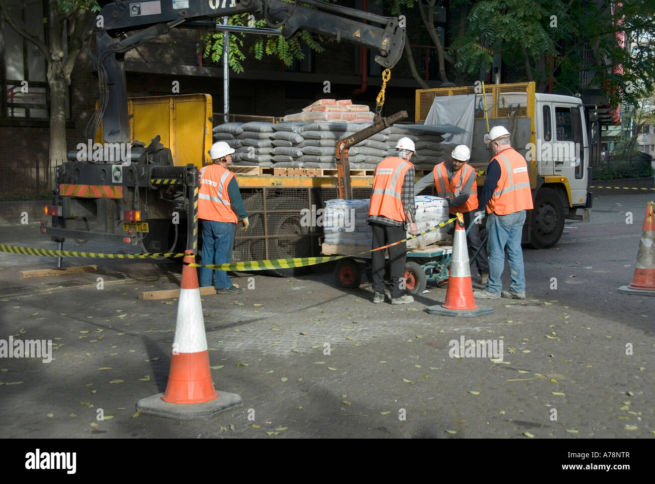 Unloading building materials off delivery lorry onto trolley adjacent ...
