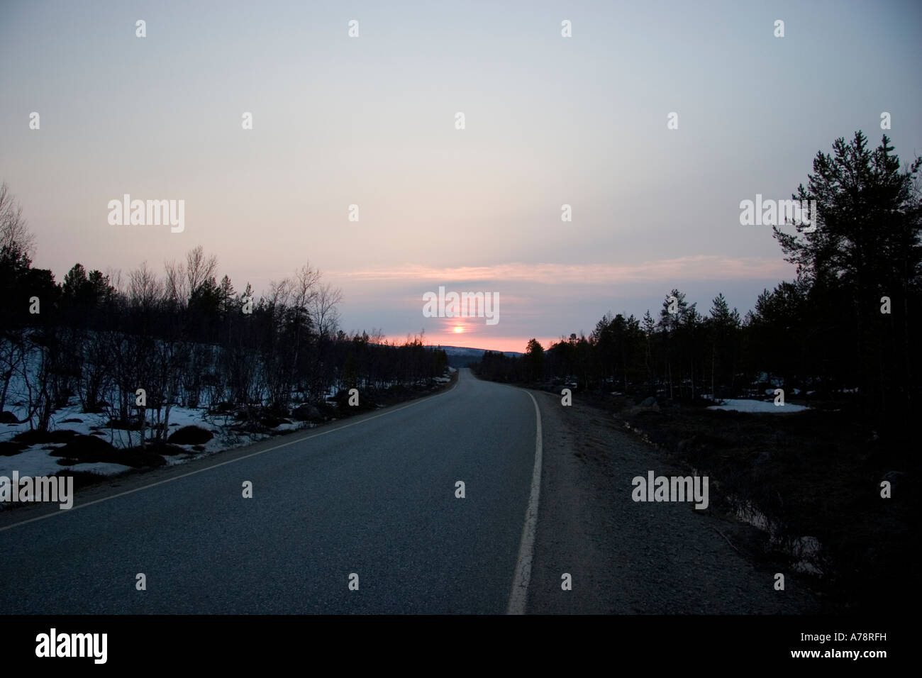 Long winding road leading to a soft sunset in the distance Stock Photo ...