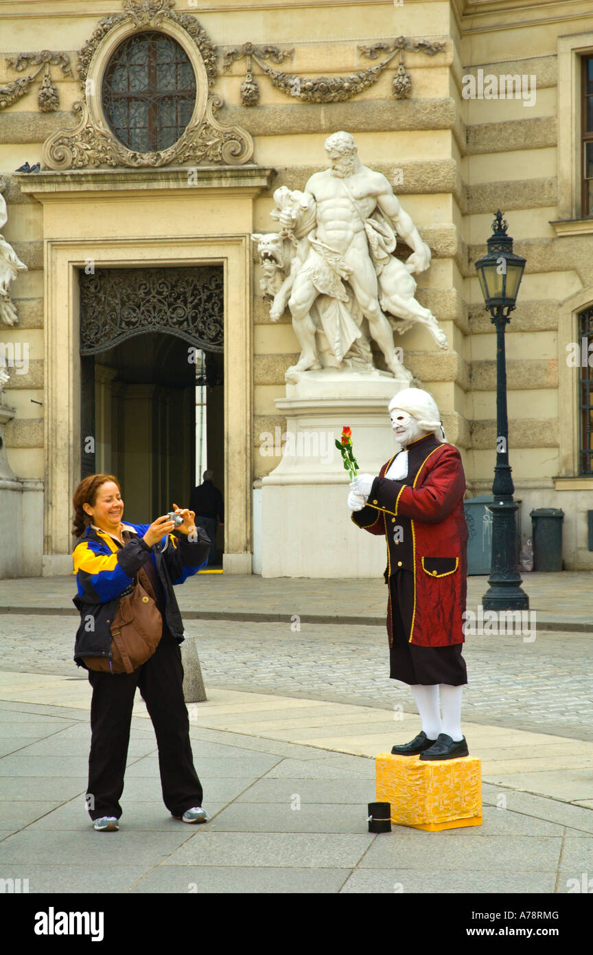 A woman taking a photo of a human statue dressed up as Mozart at ...