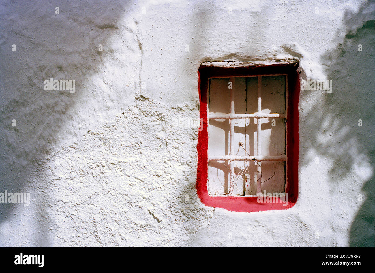 A barred window of an old whitewashed house in a white village of ...
