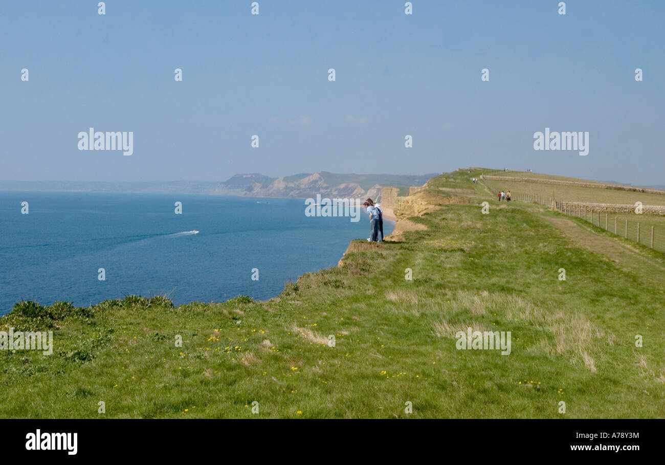 Two walkers peering over cliff edge along the Southwest Coast Path at ...
