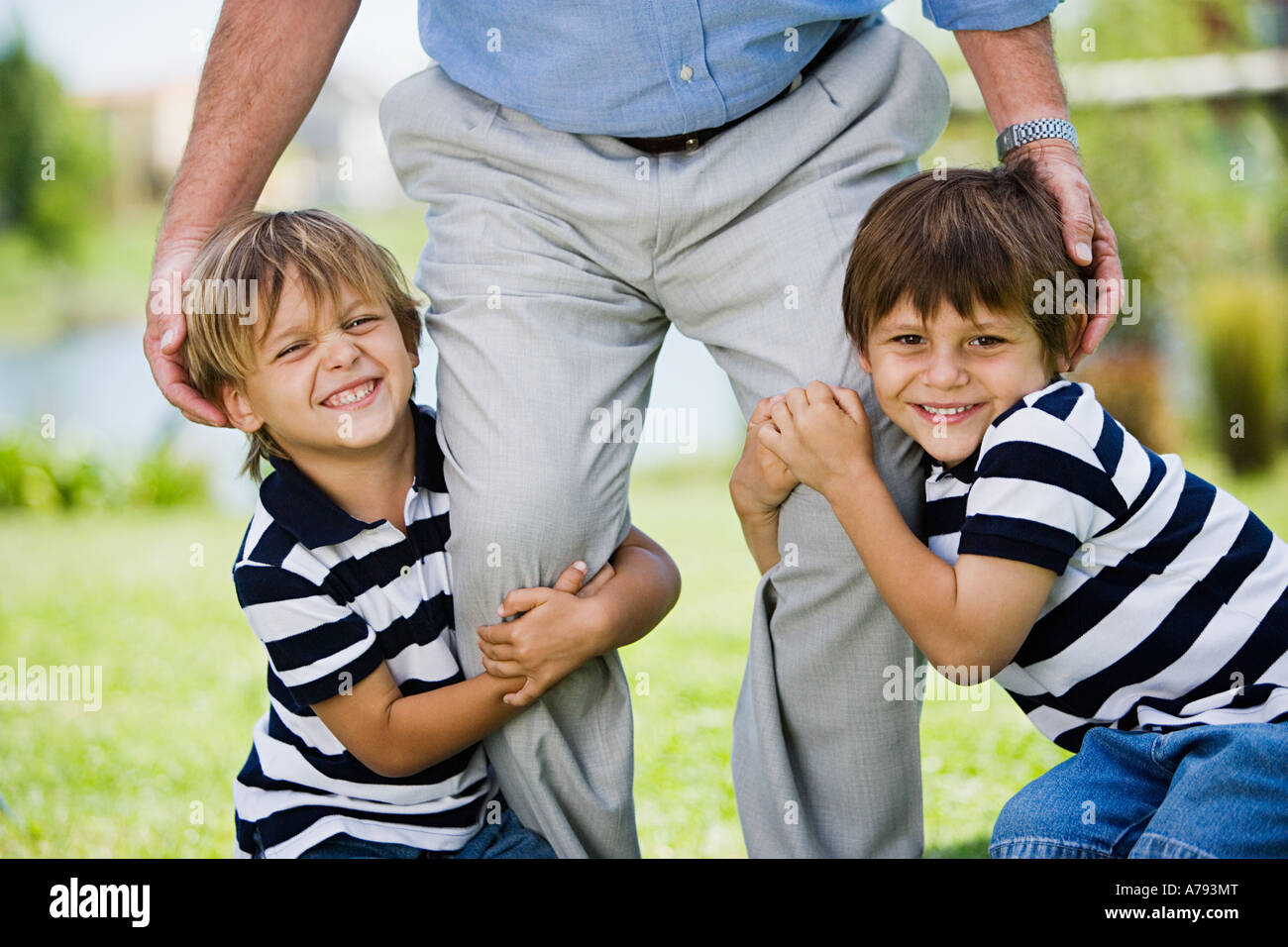 Boys grabbing fathers legs Stock Photo - Alamy