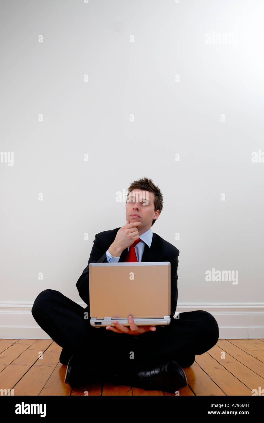 Young businessman sat cross legged thinking Stock Photo - Alamy