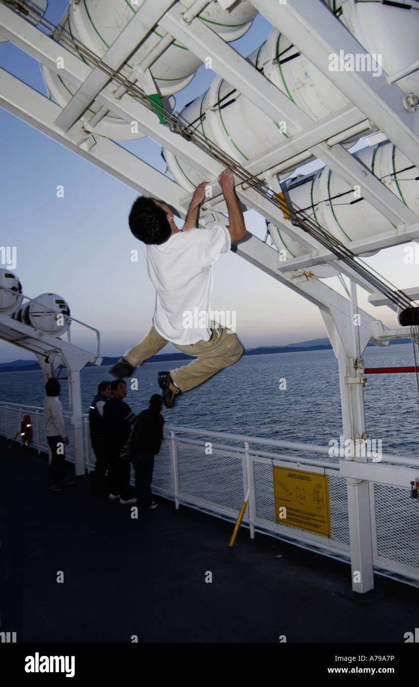 A man climbing up the life raft launching rack on a BC Ferry near ...