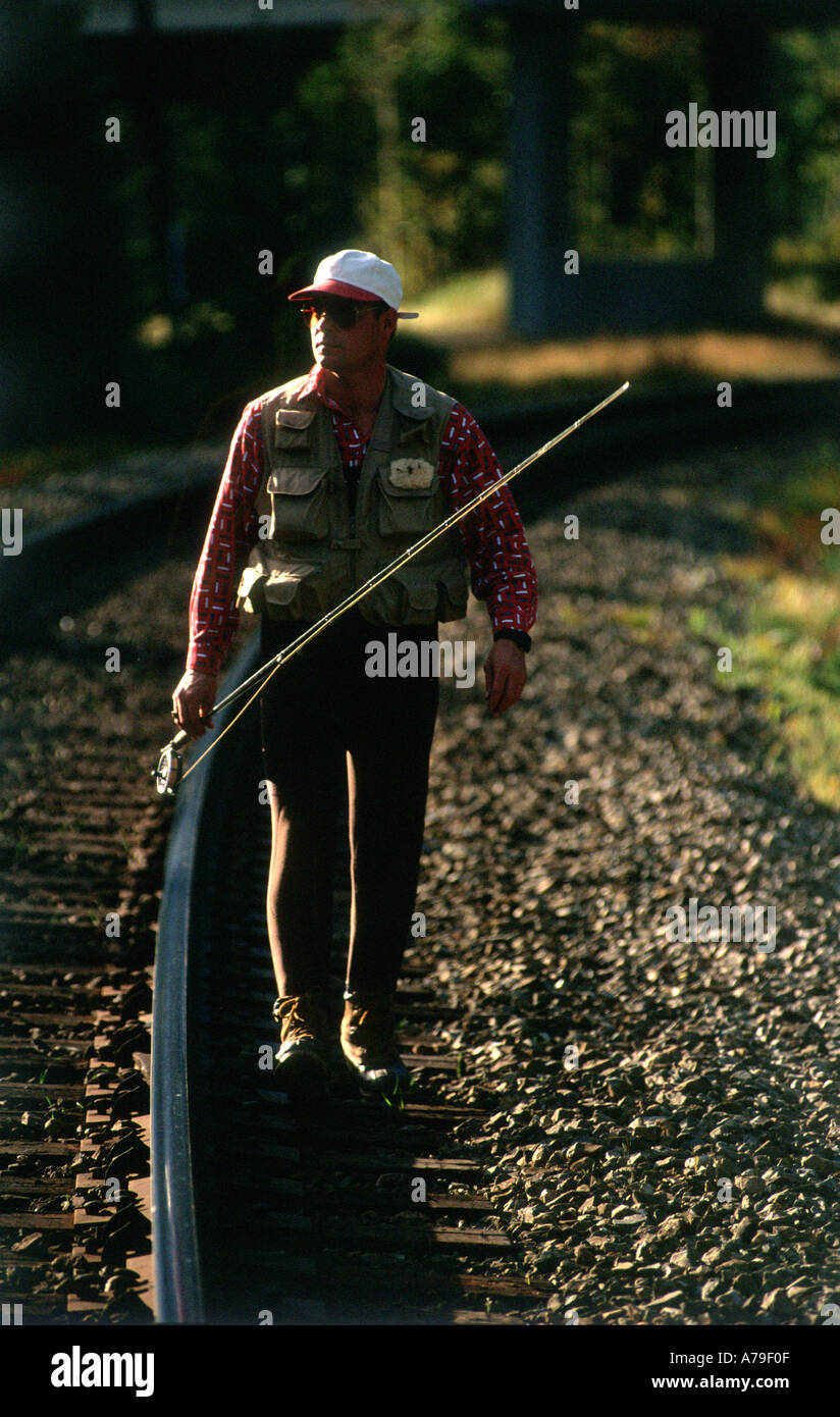 Fly fisherman walking beside railroad tracks Stock Photo - Alamy