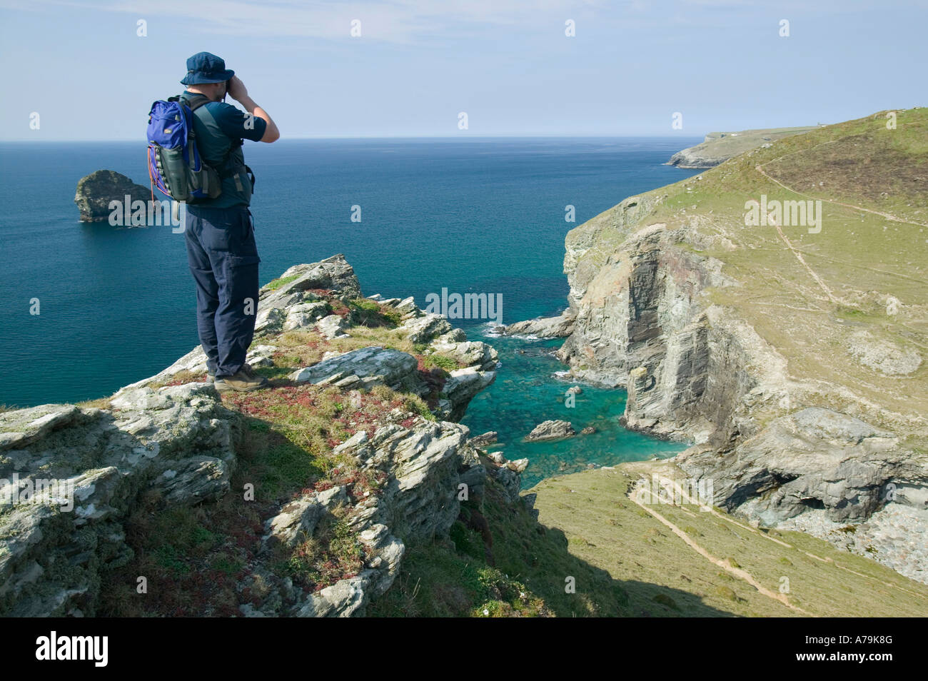 A walker looks down on old slate quarries in the sea cliff near Port ...