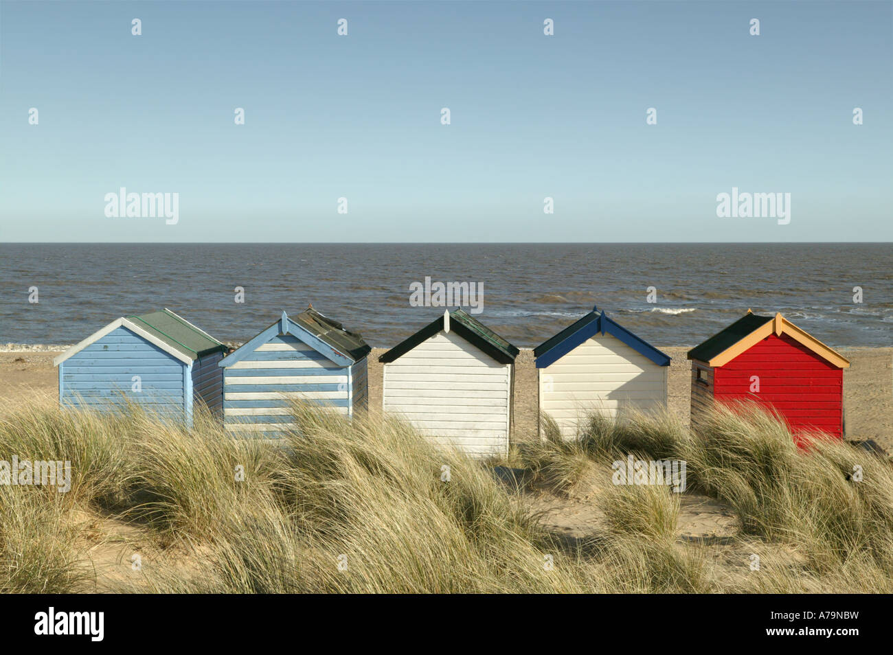 a line of colorful beach huts located in the sand dunes infront of a ...