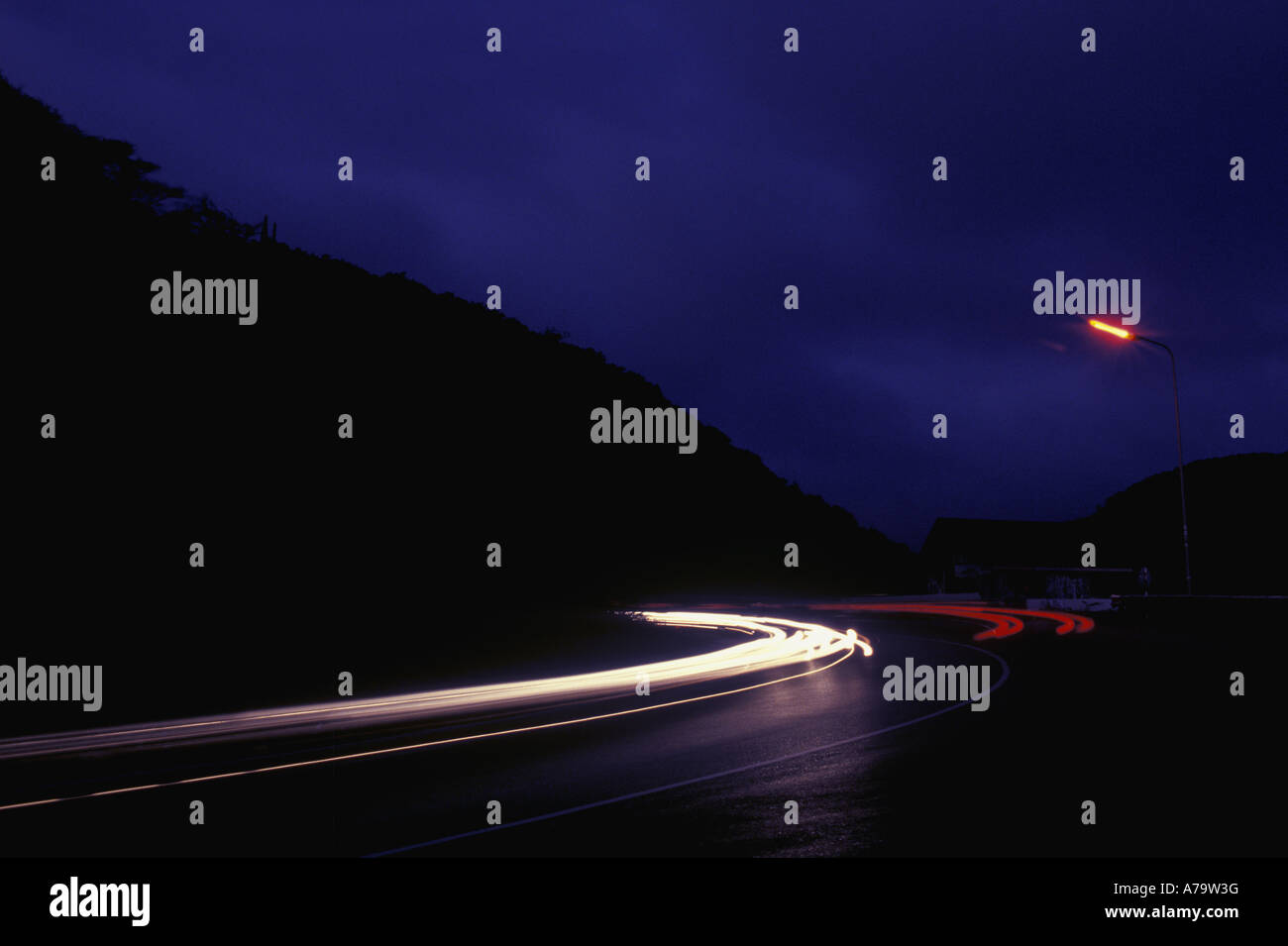 Streaking car headlights on winding road at night Stock Photo - Alamy