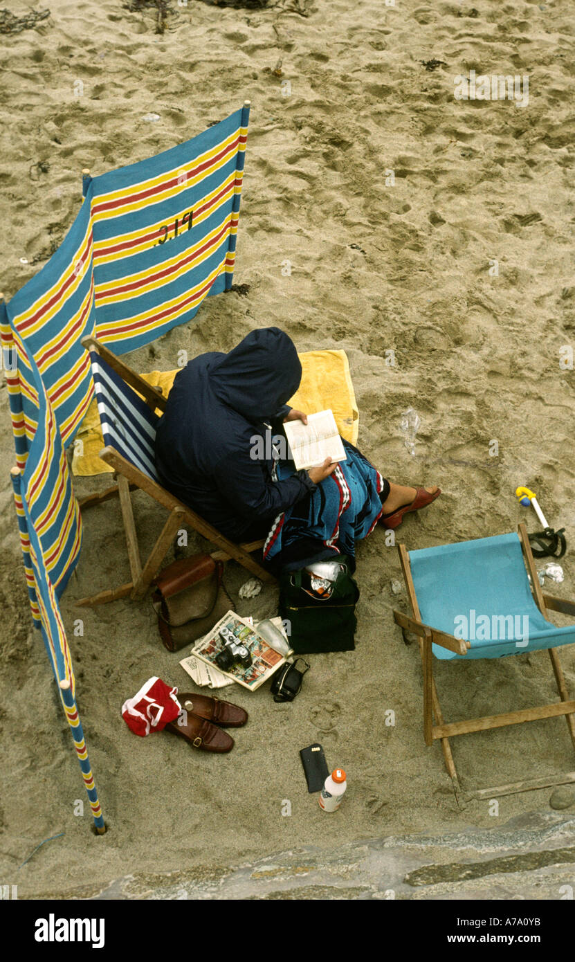Cornwall woman sheltering from rain on beach rainy Stock Photo - Alamy