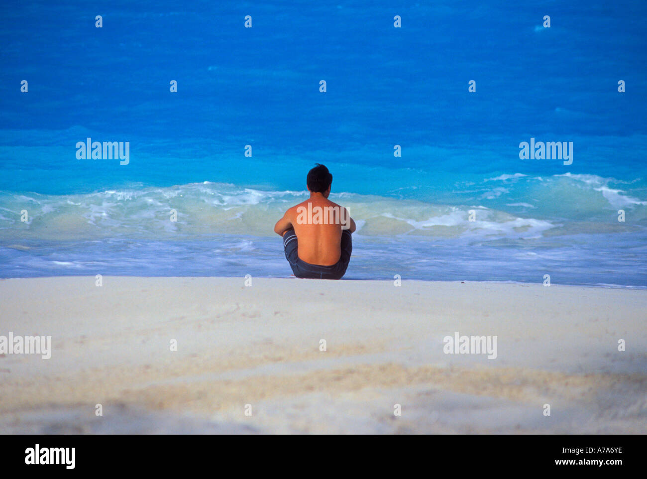 Man sitting alone, looking out to blue ocean Stock Photo - Alamy