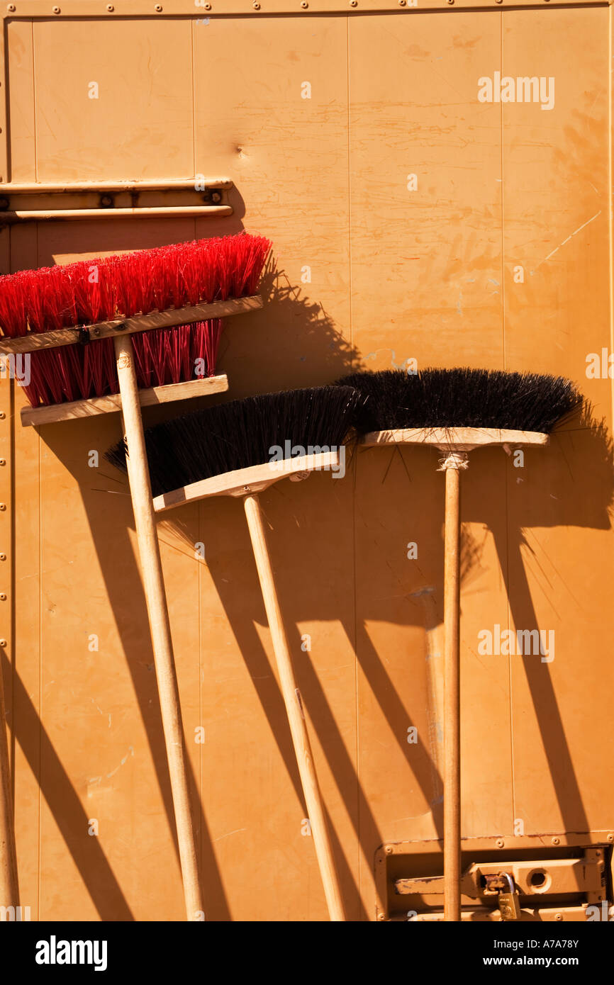 Brooms leaning against a yellow wall Stock Photo - Alamy