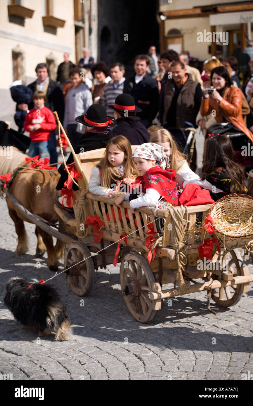 Little girls on a small carriage with dog on side. Bormio Easter parade ...