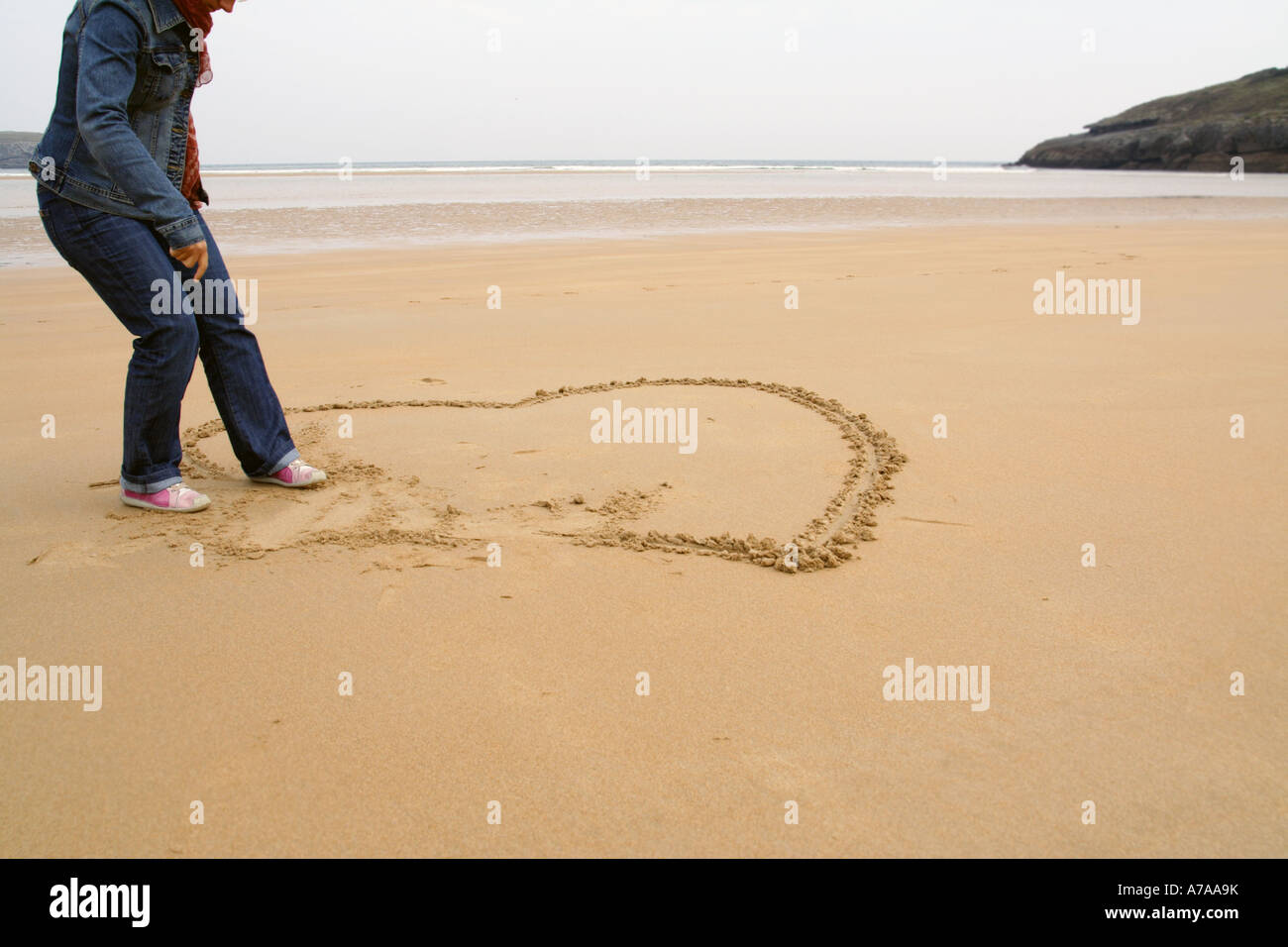 Woman erasing a heart shape drawn in the beach Stock Photo - Alamy