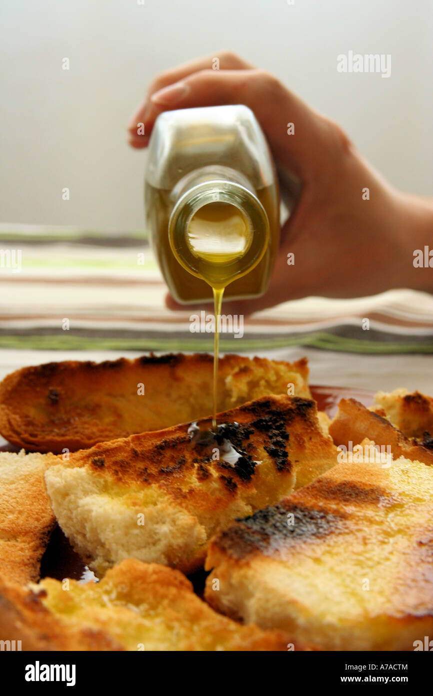 Man pouring extra-virgin olive oil on some toasts for a healthy ...