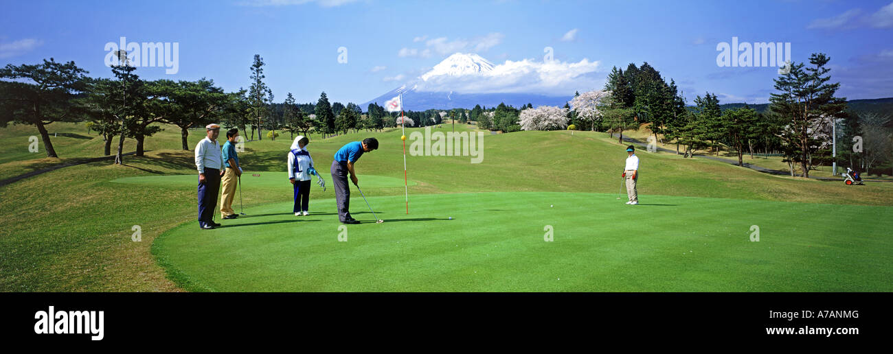 Japanese men with female caddy playing golf below Mount Fuji on Honshu ...