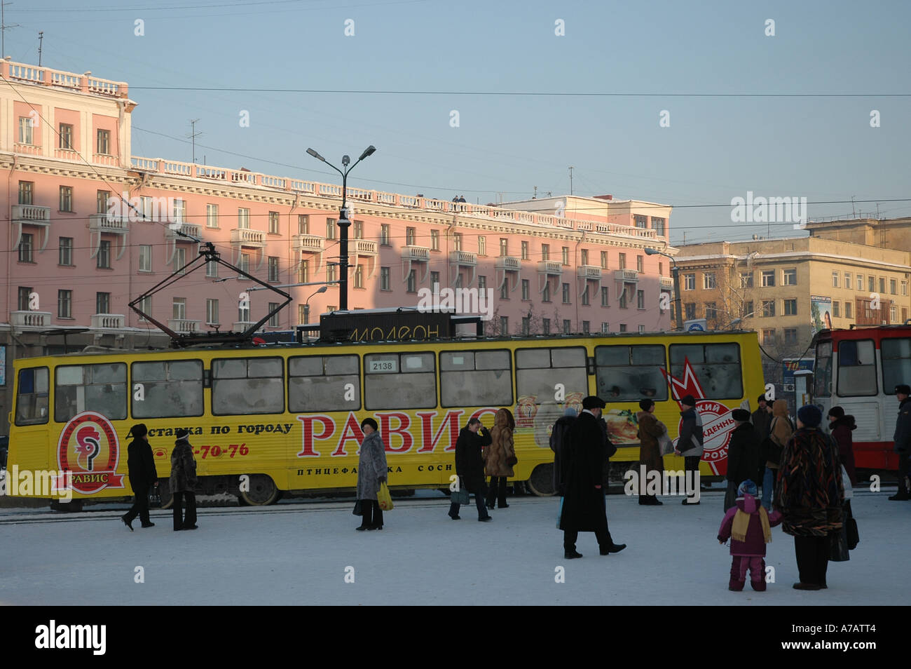 People on square with an yellow tram and a redwhite trolley bus infront ...