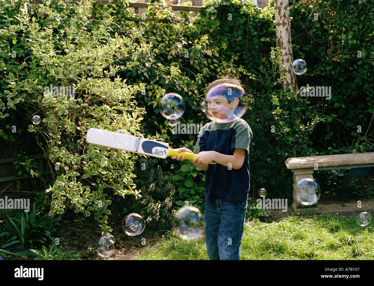boy hitting big bubbles with a cricket bat Stock Photo - Alamy