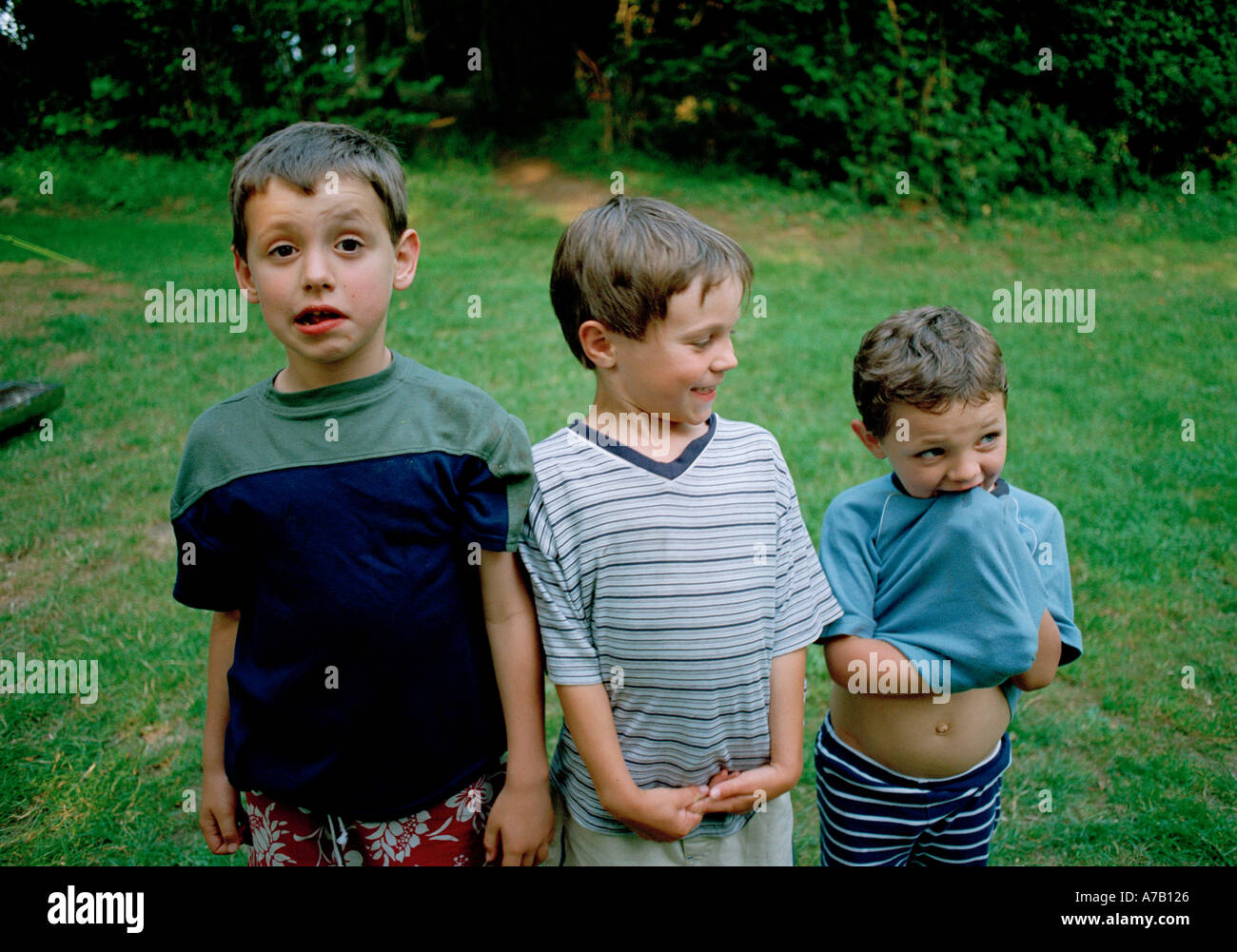 three boys standing in a row in a field facing camera Stock Photo - Alamy