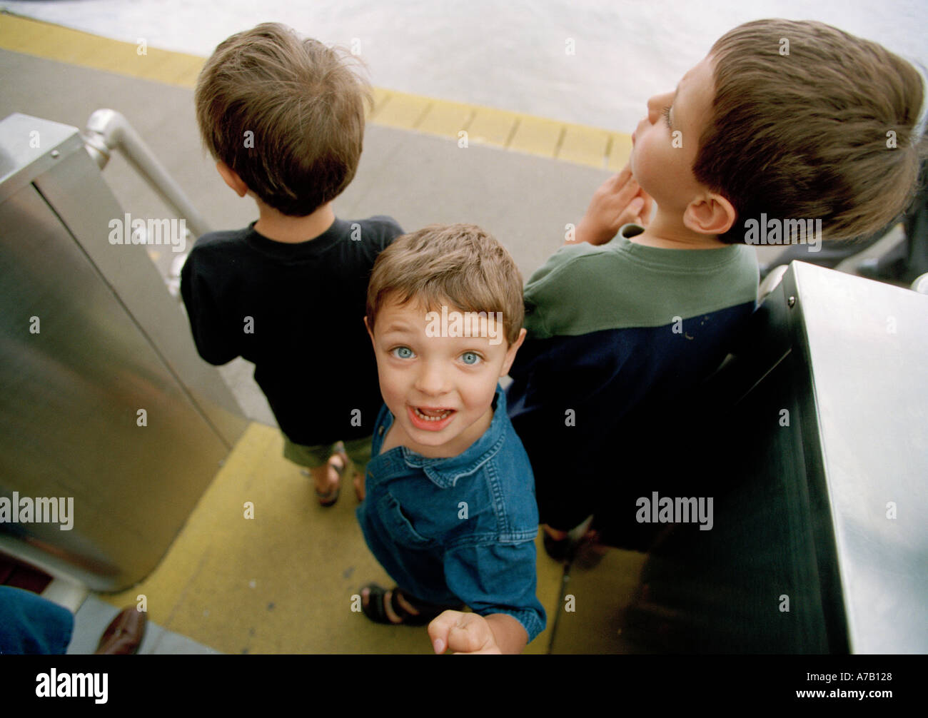 small boy turning around looking surprised up to camera with two other ...
