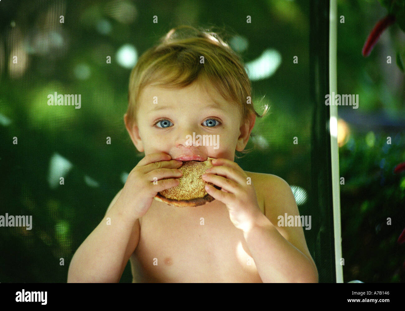 small boy biting into a burger with green background Stock Photo - Alamy