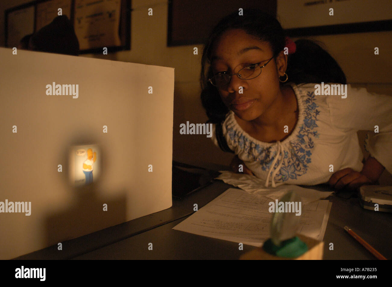 African American student doing an optics experiment in a physics class ...