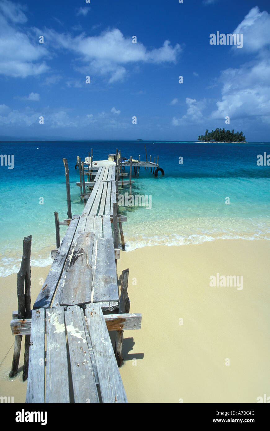 Rickety wooden dock on Caribbean beach with island with palm trees in ...