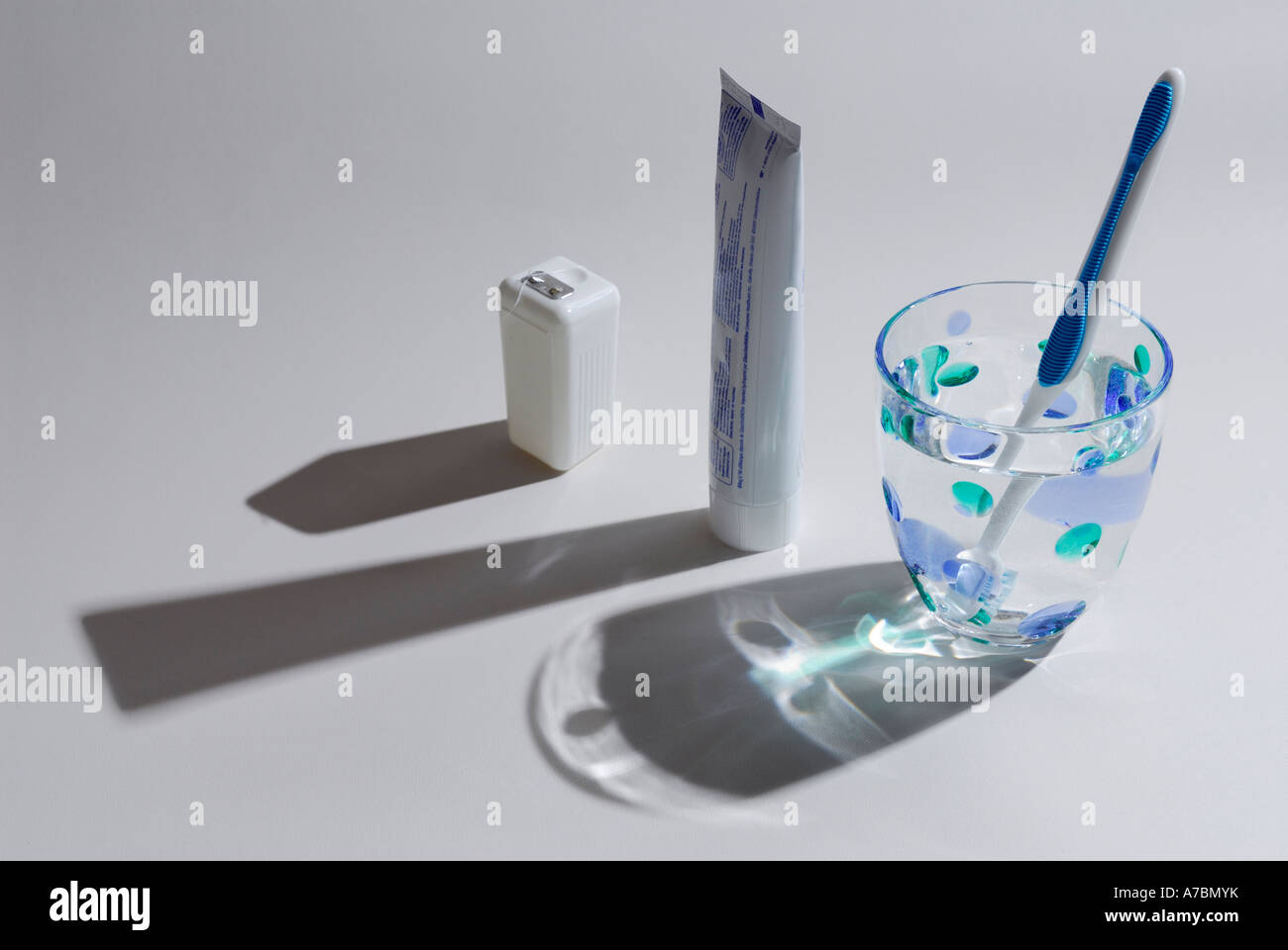 Shadows of toothpaste floss and toothbrush in cup on white Stock Photo ...
