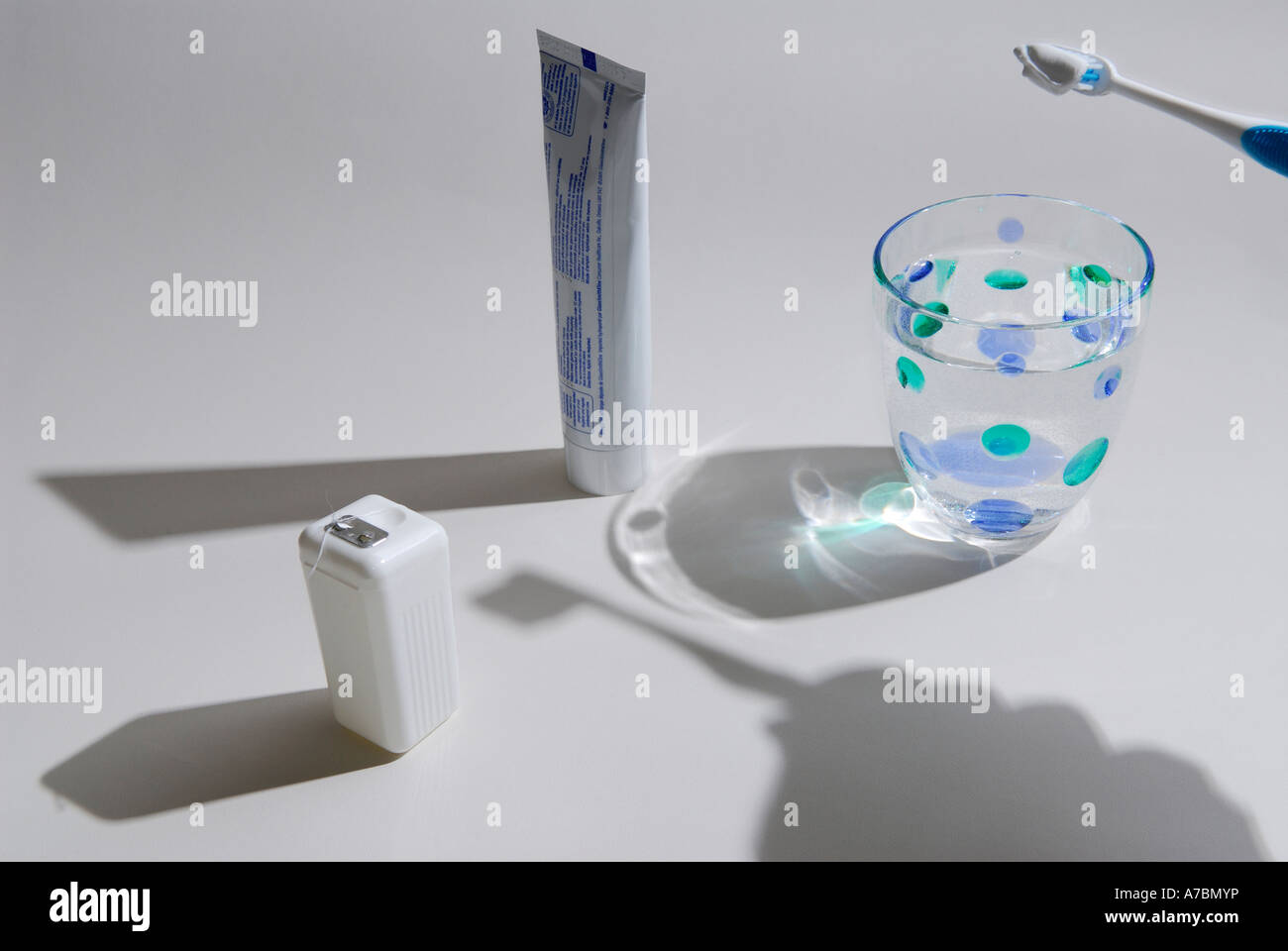Toothpaste floss cup and shadow of toothbrush on white Stock Photo - Alamy