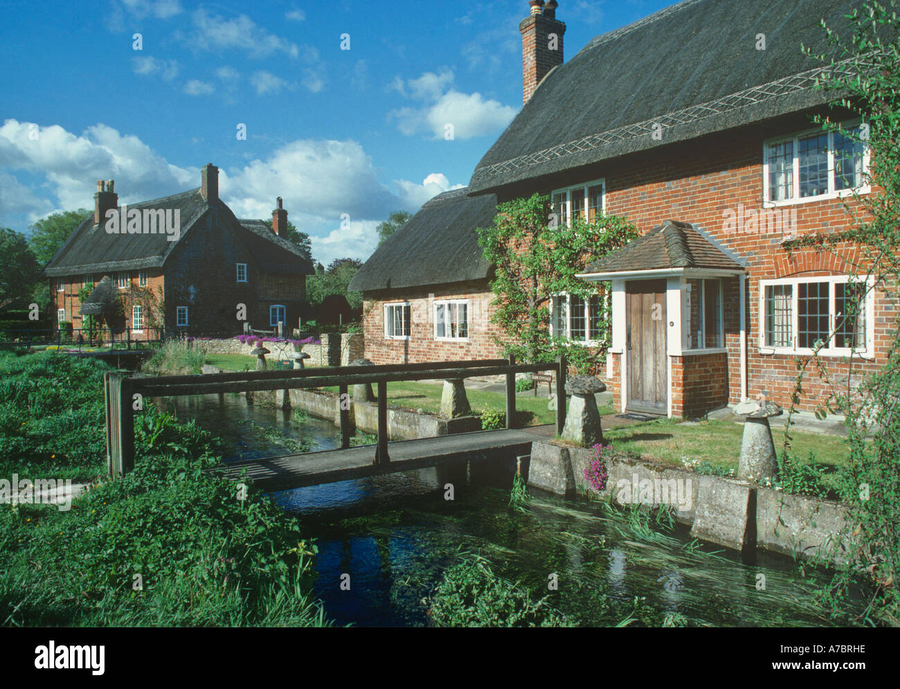Thatched cottages beside a chalk stream in the pretty village of ...