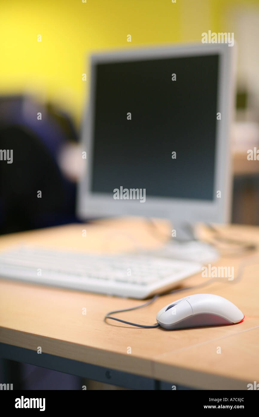 Flat computer monitor screen and mouse in large open plan office ...
